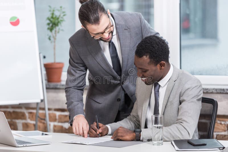 Multiethnic Businessmen Smiling and Signing Document Stock Photo ...