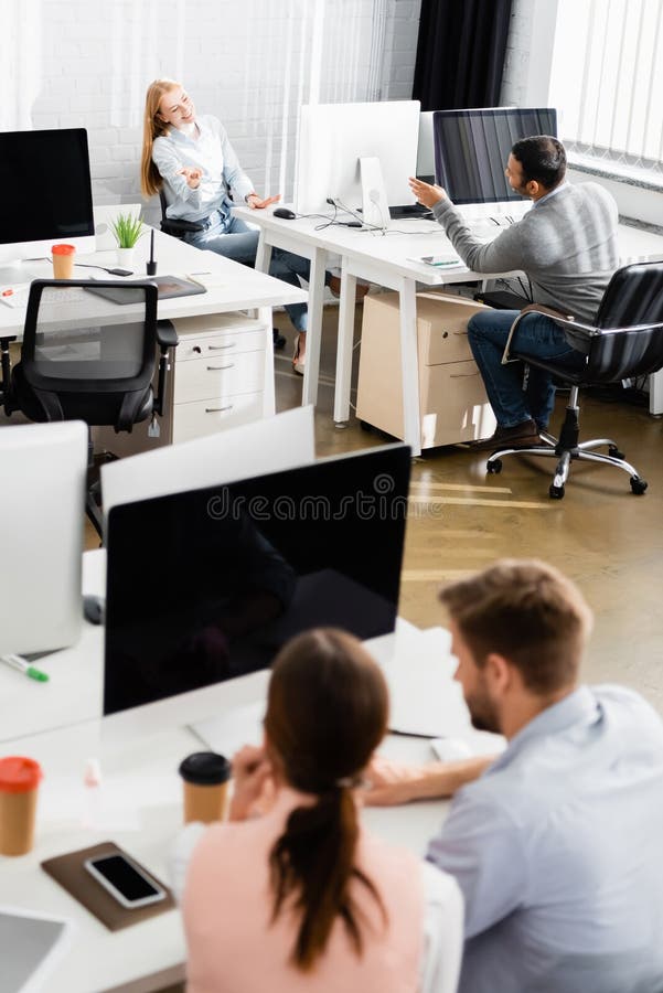 Multiethnic Businesspeople Talking while Using Computers Stock Image ...