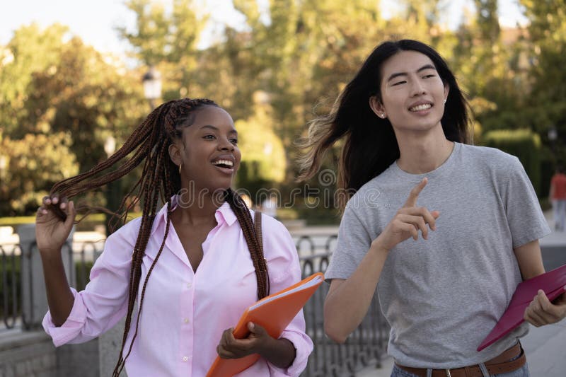 Multiethnic Couple of Students Smiling and Pointing with the Finger ...