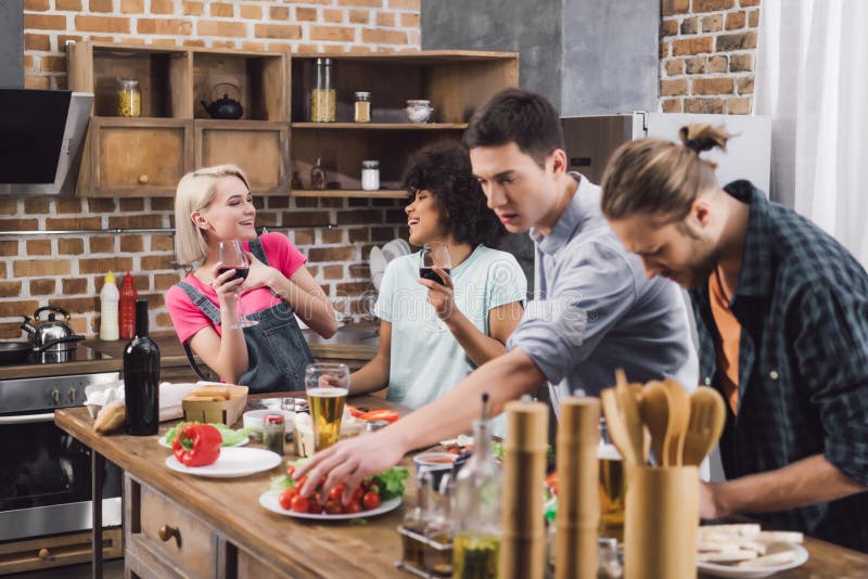 Multiethnic Girls Drinking Wine while Men Cooking Stock Image - Image ...