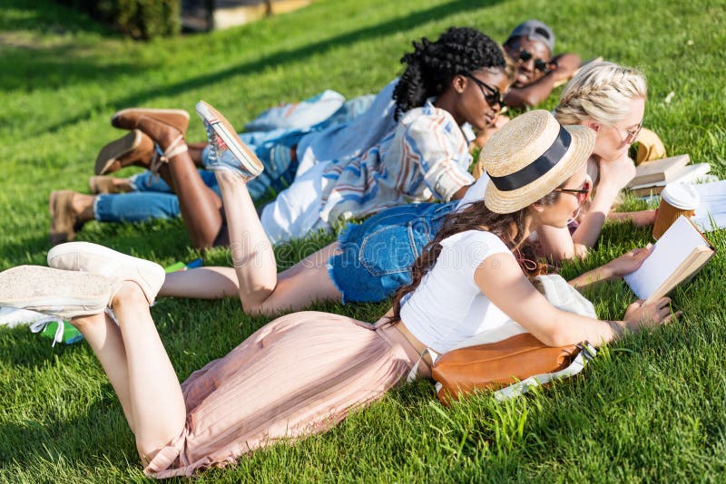 Multiethnic Students Reading Books while Lying on Grass and Studying in ...