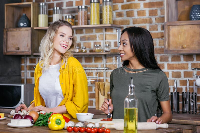 Multiethnic Women Cooking Pizza and Smiling Each Other in Kitchen Stock ...