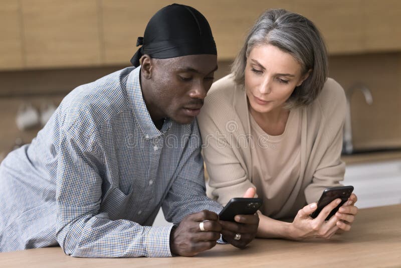 Multinational Mature Couple Using Two Smartphones Spend Time Together ...