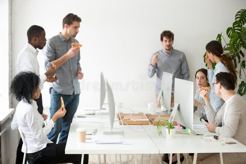 Multinational Work Group Talking and Eating Pizza at Workplace Stock ...