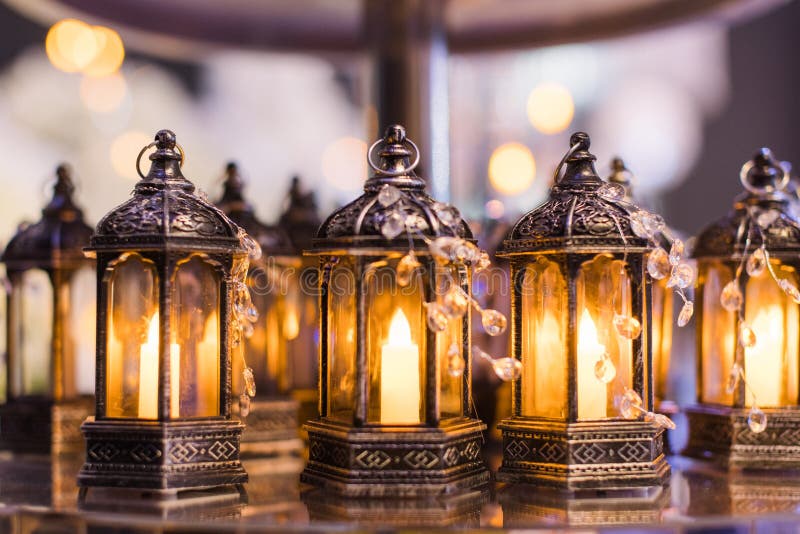 Multiple Candles Illuminate Rows of Lamps on a Table. Stock Image ...