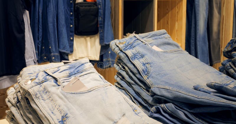 Multiple Stacks of Folded Blue Jeans Sit on a Wooden Display Table in a ...