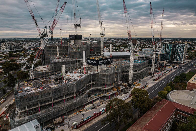 Tall Construction Cranes Stand Over a Bustling Cityscape, with a Large ...