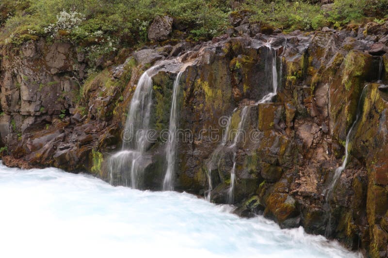 Multiple Thin Waterfalls Falling Over a Bare Red Rock into a Rapid ...