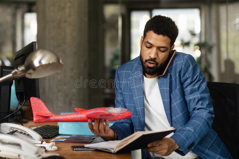 Multiracial Businessman Working in the Office, Holding Model of Plane ...