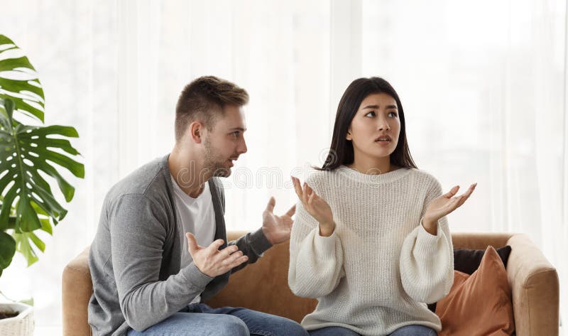 Multiracial Couple Arguing Sitting On Couch At Home During Quarantine