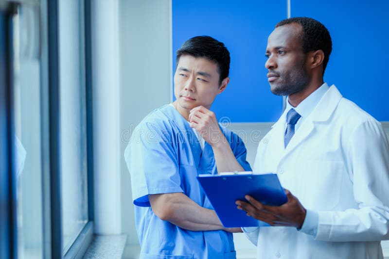 Multiracial Group of Doctors in Medical Uniforms with Folder in Clinic ...