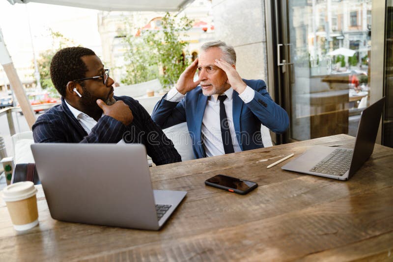 Multiracial Men Talking and Gesturing while Working with Laptops in ...