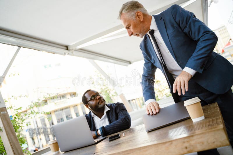 Multiracial Men Talking while Working with Laptops in Cafe Stock Image ...