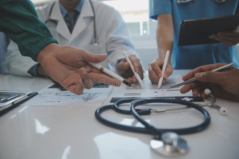 Multiracial Team of Doctors Discussing a Patient Standing Grouped in ...