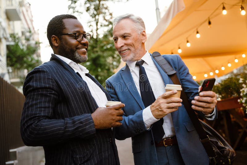 Multiracial Two Men Using Cellphone and Talking while Drinking Coffee ...