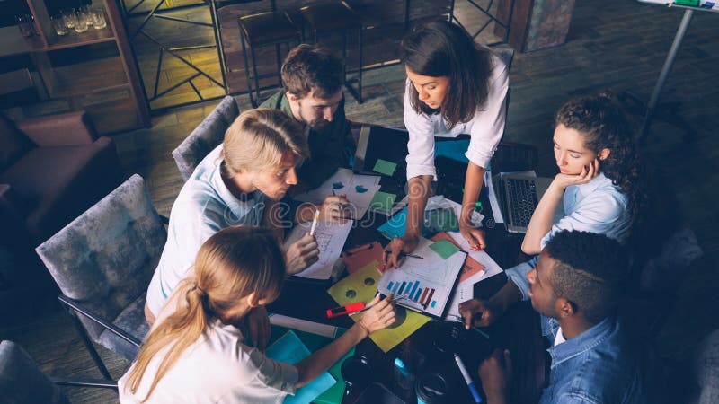 Multiracial Workgroup is Analyzing Diagram and Writing on Stickers ...