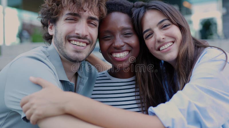 Multiracial Young Friends Laughing while Hugging Each Other Sitting ... Multiracial Young Friends Laughing while Hugging Each Other Sitting ...