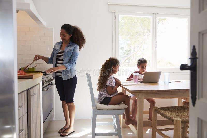 Mum Cooking while Kids Work at Kitchen Table, from Doorway Stock Photo ...