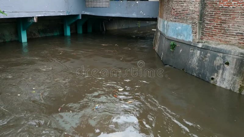 A Murky River Flows Beneath a Building with a Brick Wall, Capturing an ...