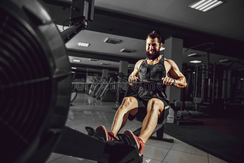 Muscular Fit Man Using Rowing Machine at Gym Stock Photo - Image of ...