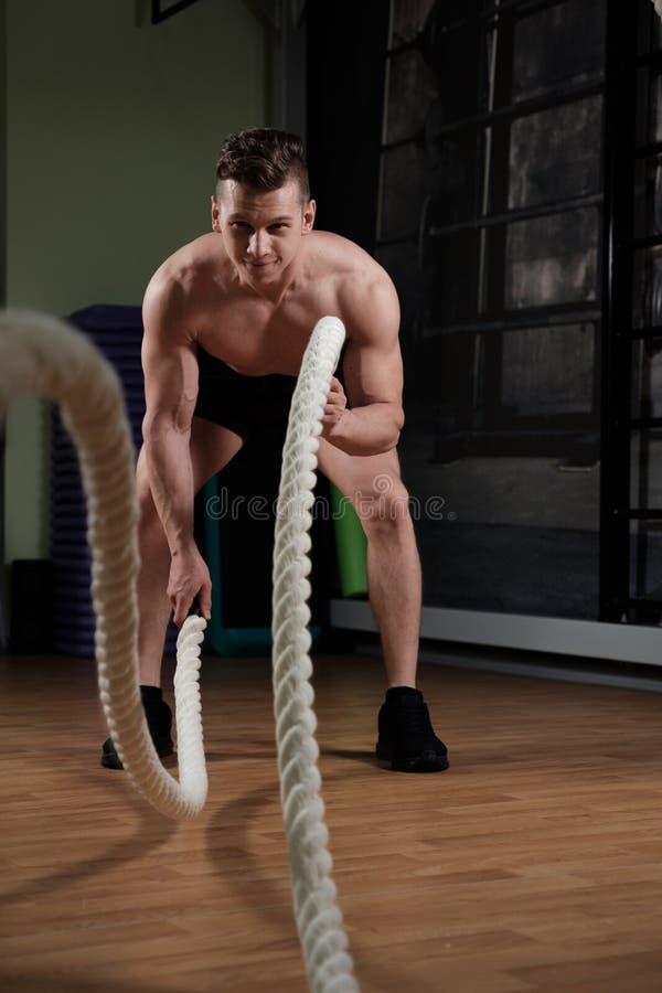 Muscular Man with Battle Rope Doing Exercise in Functional Training Gym ...