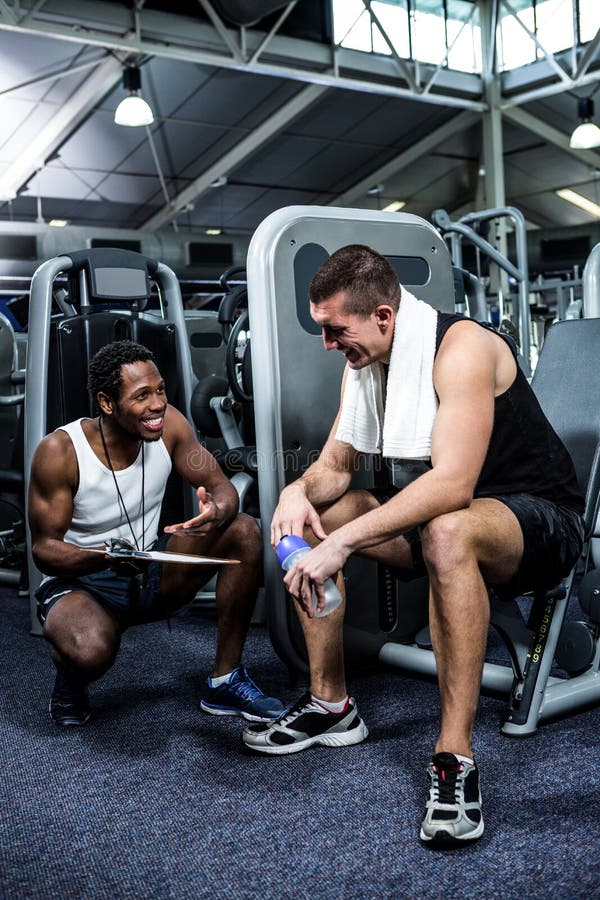 Muscular Man Discussing Performance with Trainer Stock Photo - Image of ...