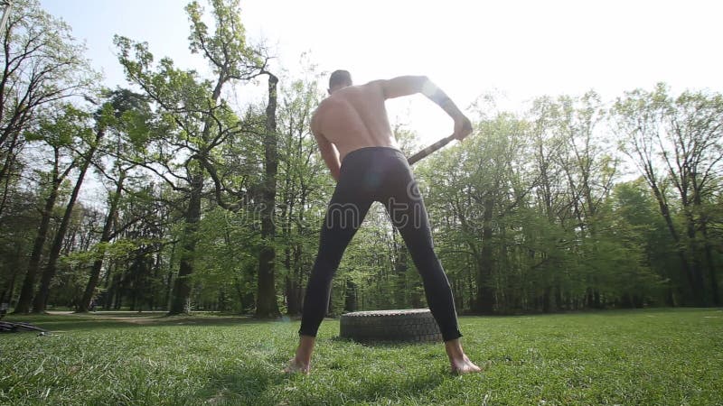 Muscular Man Hitting Tire with a Hammer, Shoot from Behind Stock ...