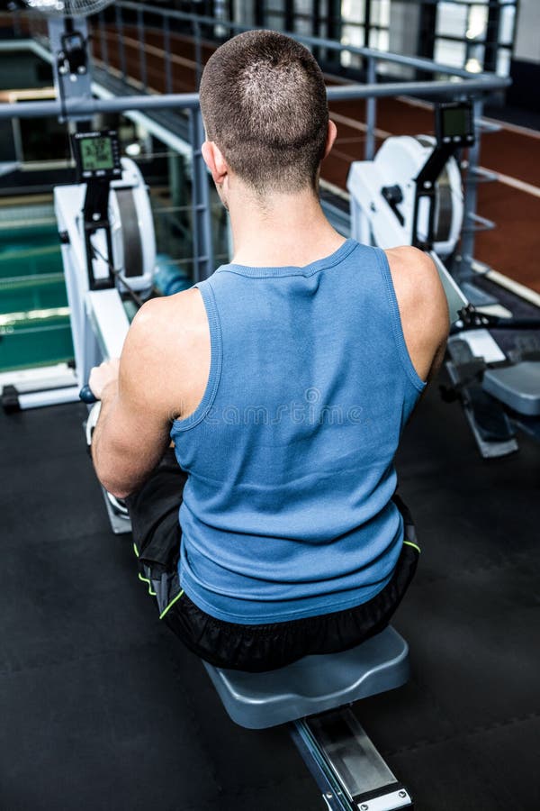 Muscular Man Using Rowing Machine Stock Photo - Image of exercising ...