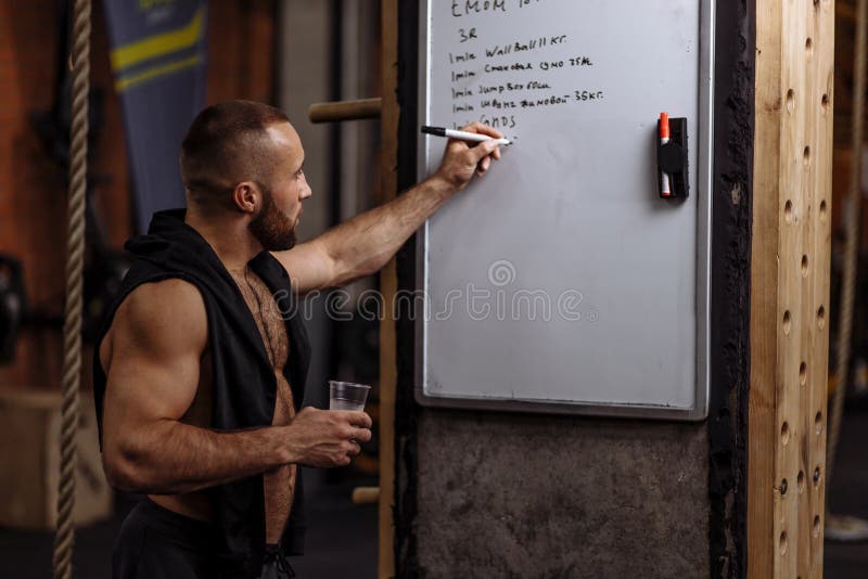 Muscular Man is Writing Workout Routine on the Flipchart while Having a ...