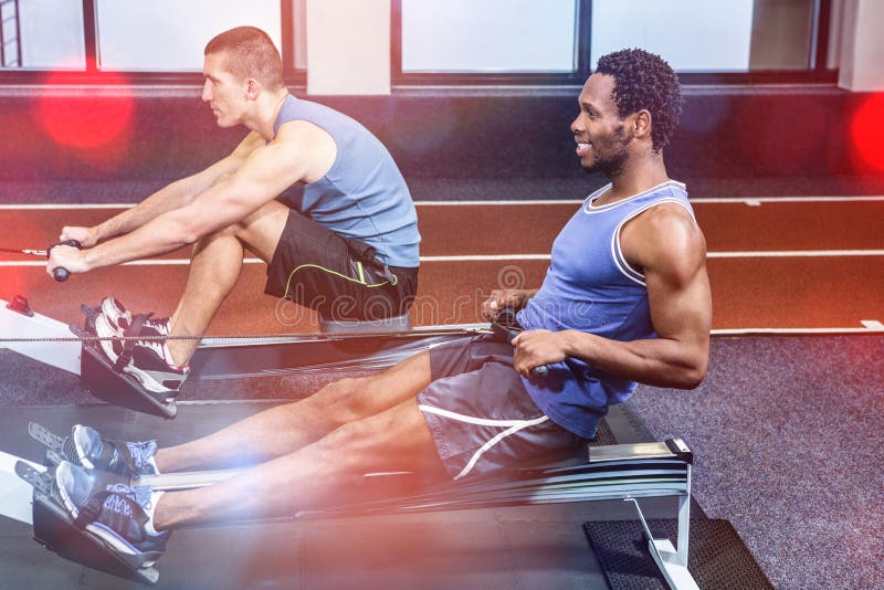 Muscular Men Using Rowing Machine Stock Photo - Image of focused, male ...