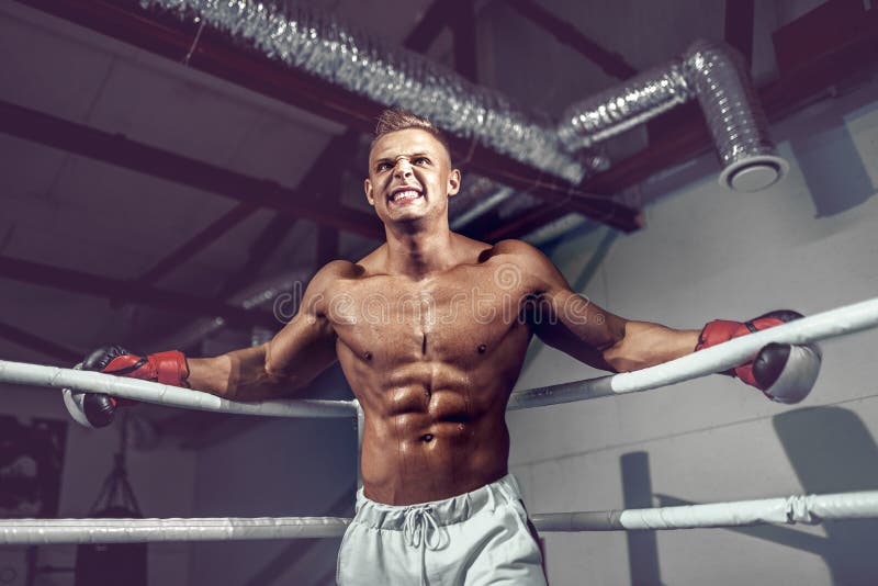 Muscular Professional Kick Boxer Resting on the Ropes in the Corner of ...