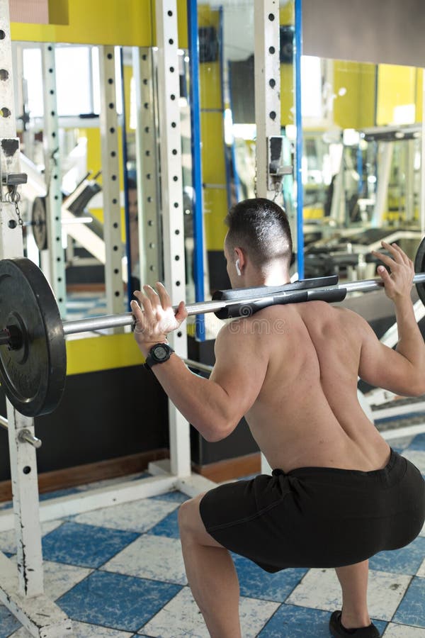 Muscular Young Man Performing Squat Exercises with Weights Stock Photo ...
