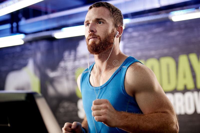 Music Keeps Him Moving. a Young Man Working Out on a Treadmill at the ...