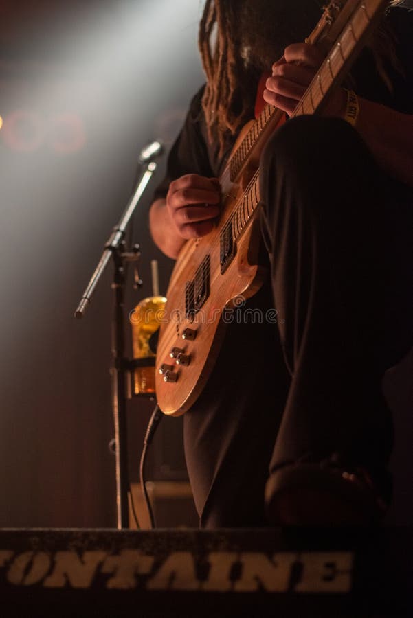 A Musician with Dreadlocks Standing on Stage Playing Electric Guitar ...