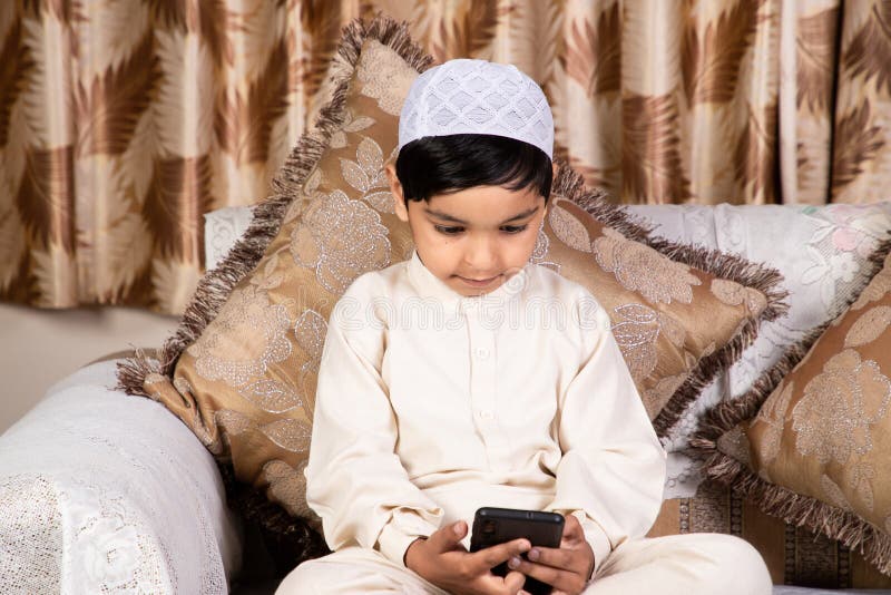 Muslim Child Using Mobile Phone at Home while Sitting on Sofa Stock ...