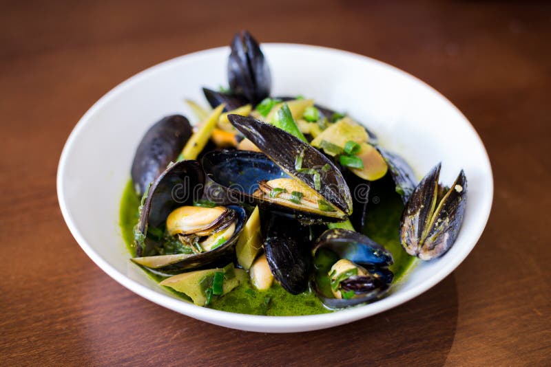 Mussels in Shells in a White Bowl with a Green Sauce on a Dining Table ...