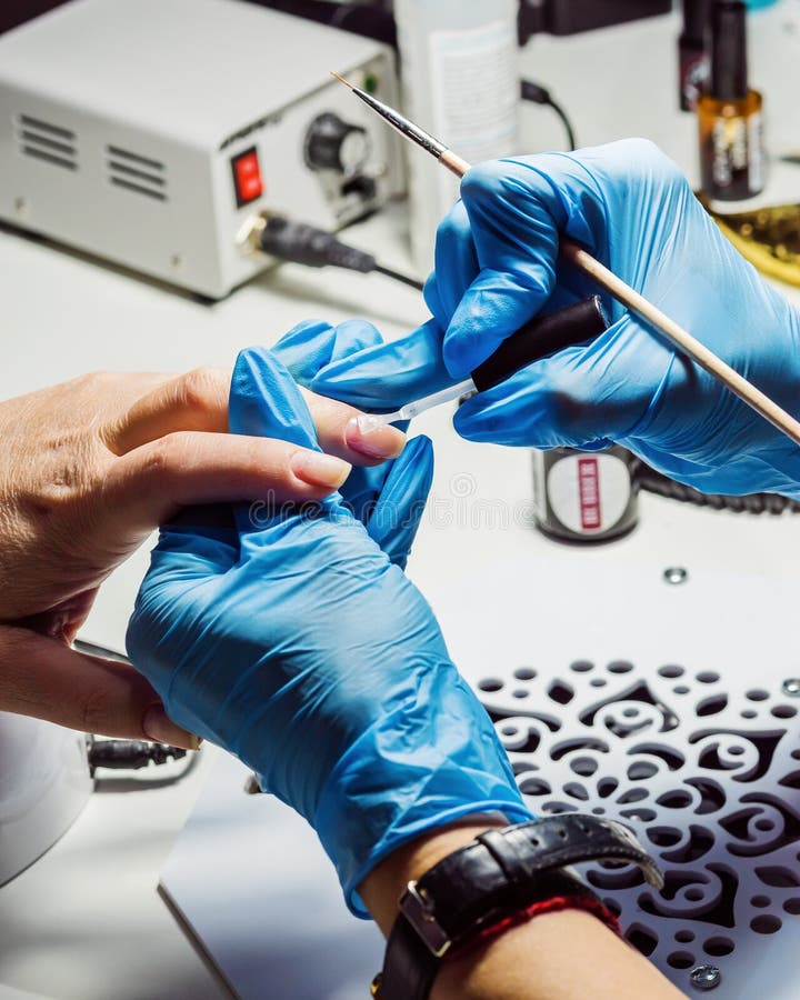 Worker in a Nail Salon, Paints Artificial Extension Nails at the ...