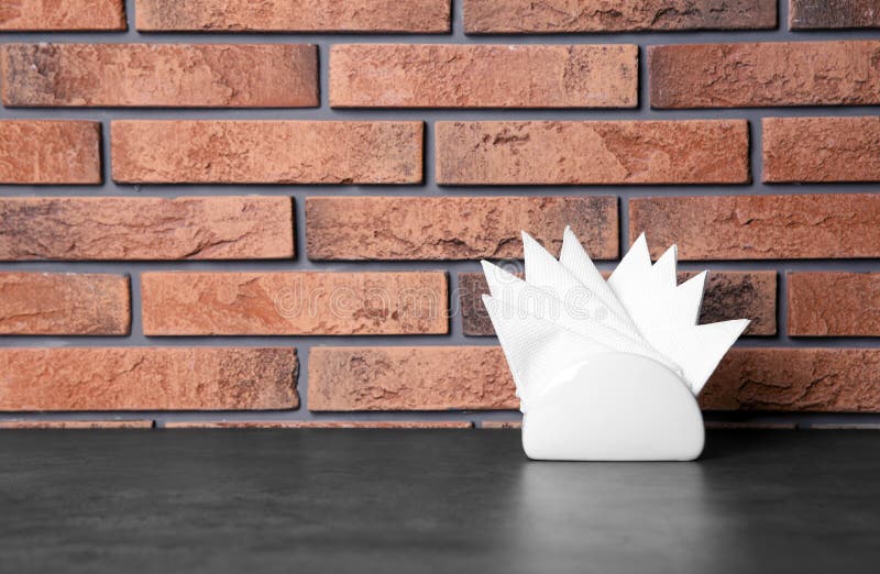 Napkin Holder with Paper Serviettes on Table Against Brick Wall. Stock ...