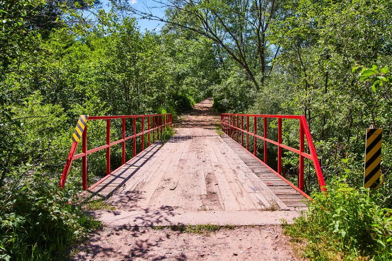 Narrow Bridge with Vibrant Red Railing through Woods Stock Image ...
