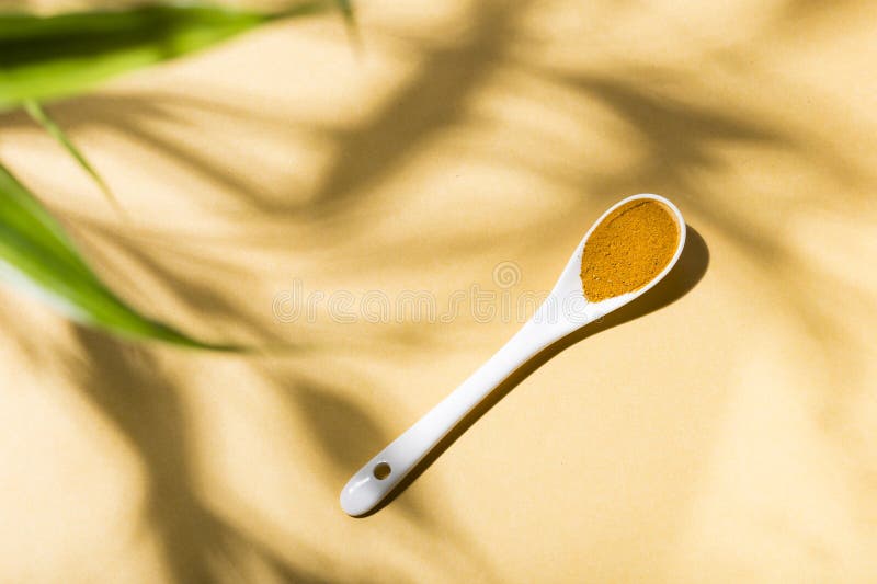 Naturally Vibrant: Turmeric in a White Spoon on a Yellow Background ...