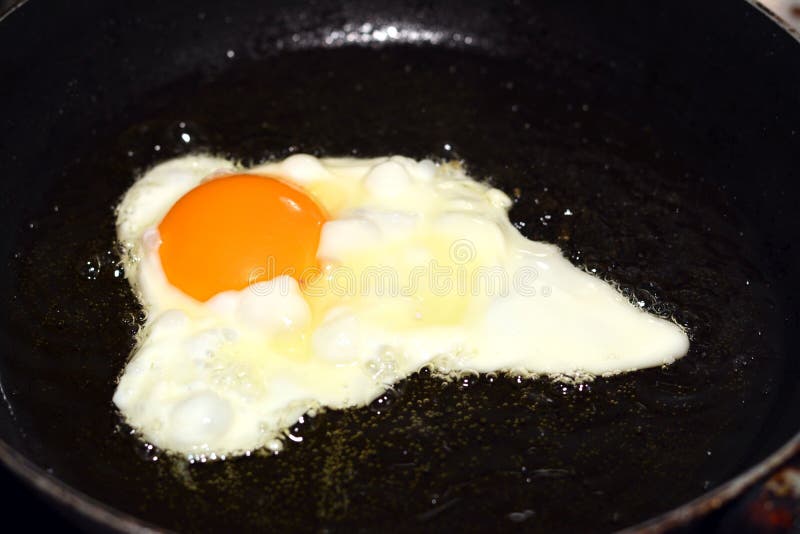 Nearly Done Fried Egg in a Black Pan and Boiling Oil Stock Photo ...