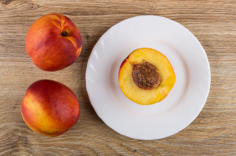 Nectarines and Half of Nectarine in Plate on Wooden Table Stock Photo ...