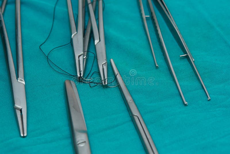 Needle Holders with Needles and Sutures and Scissors on Operating Table ...