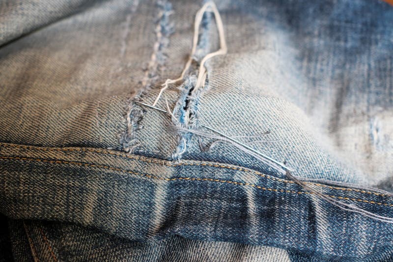 A Needle and Thread Sew Up a Hole in a Denim. Work of a Seamstress or ...