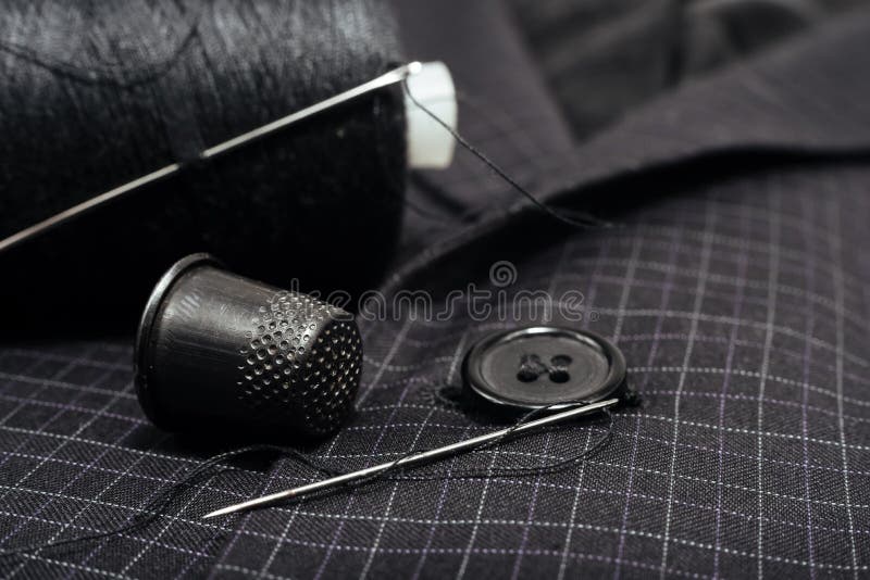 A Needle and Thread Sews Up a Button on a Plaid Suit. Thimble Stock ...