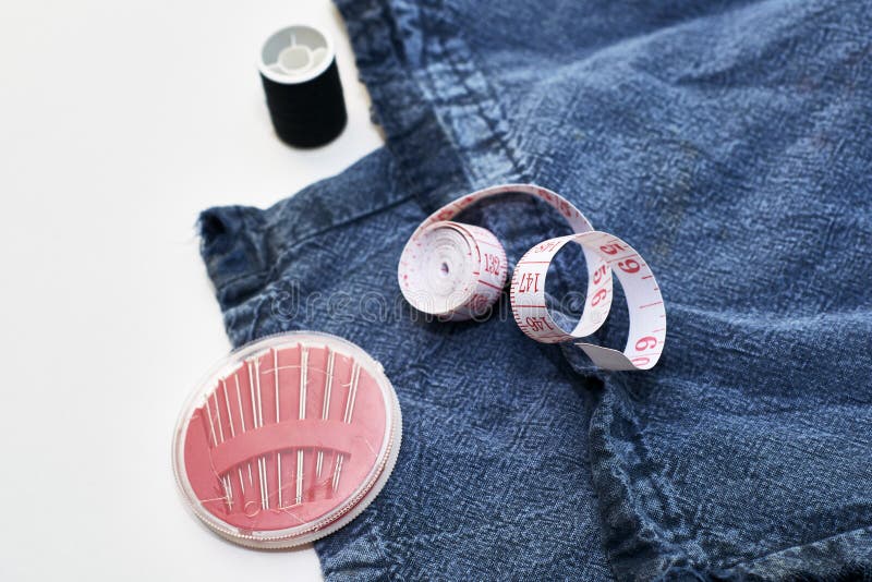 Needles Measuring Tape and Thread on the Background of Torn Jeans the ...