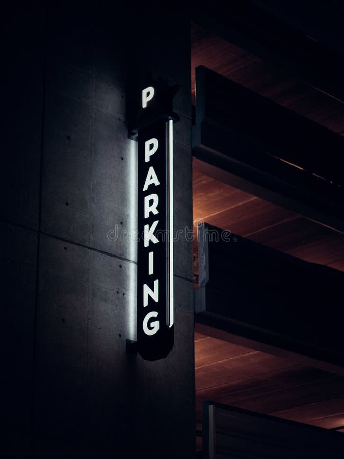 Neon Parking Sign Illuminated at Night on a Concrete Wall of a Parking ...