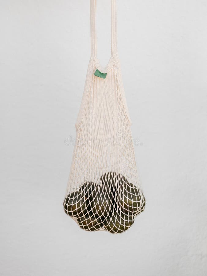 A Net Bag Filled with a Bunch of Avocado on White Background Stock ...