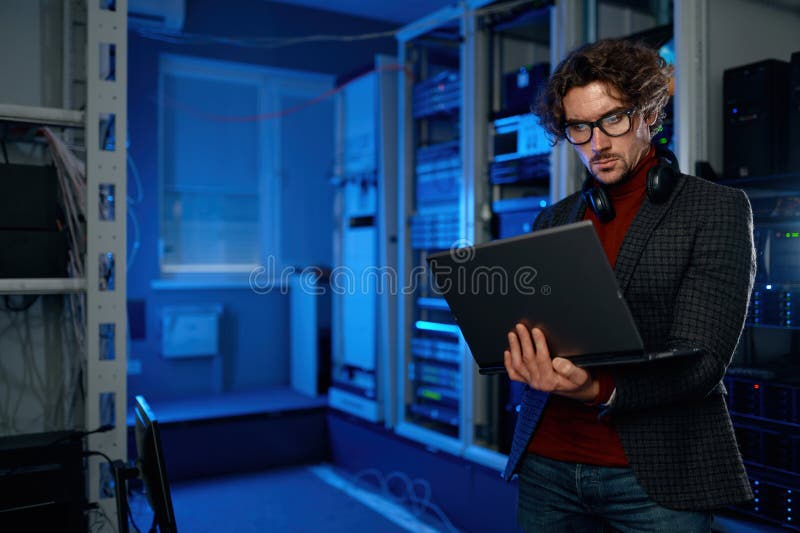 Network Engineer Using Digital Tablet in Server Room during Maintenance ...