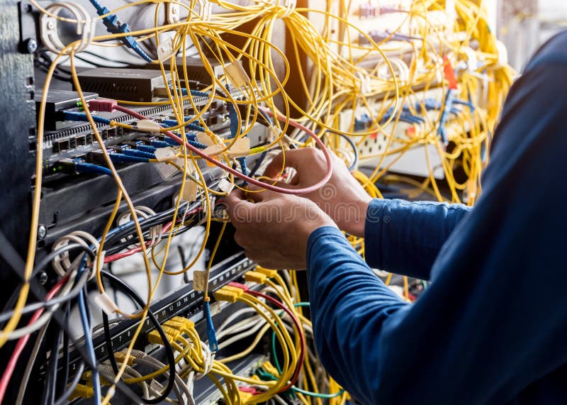 Network Engineer Working in Server Room. Connecting Network Cables To ...